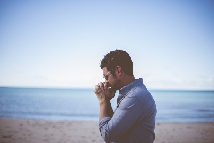 Man Praying on Beach