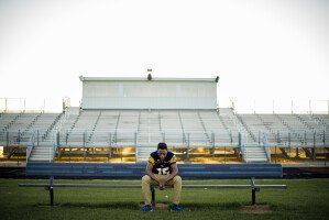 Football Player Praying on Bench
