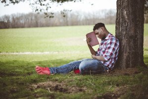Man Praying With Bible Under Tree